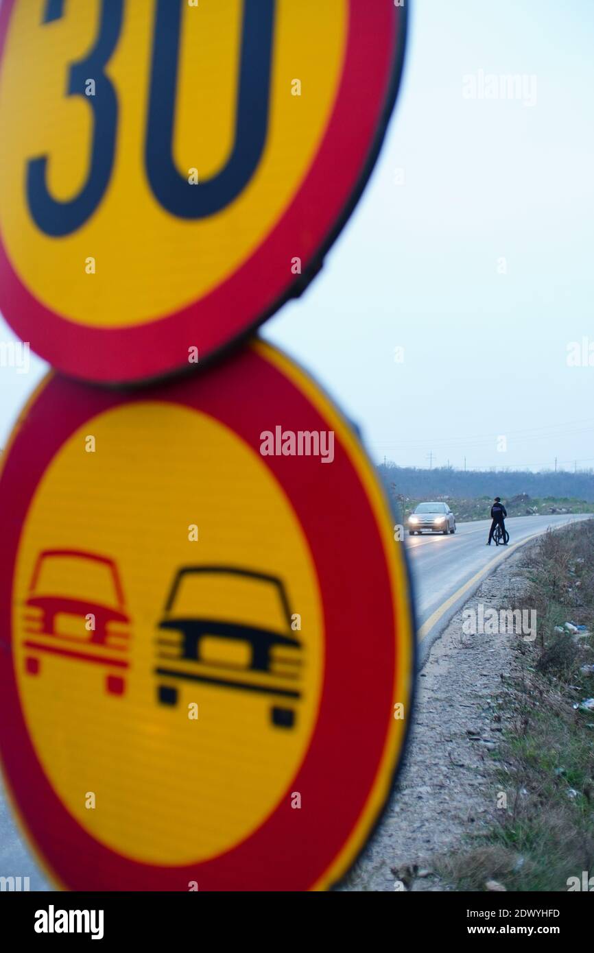 A vertical shot of a 30 speed limit and NO OVERTAKING sign along the ...