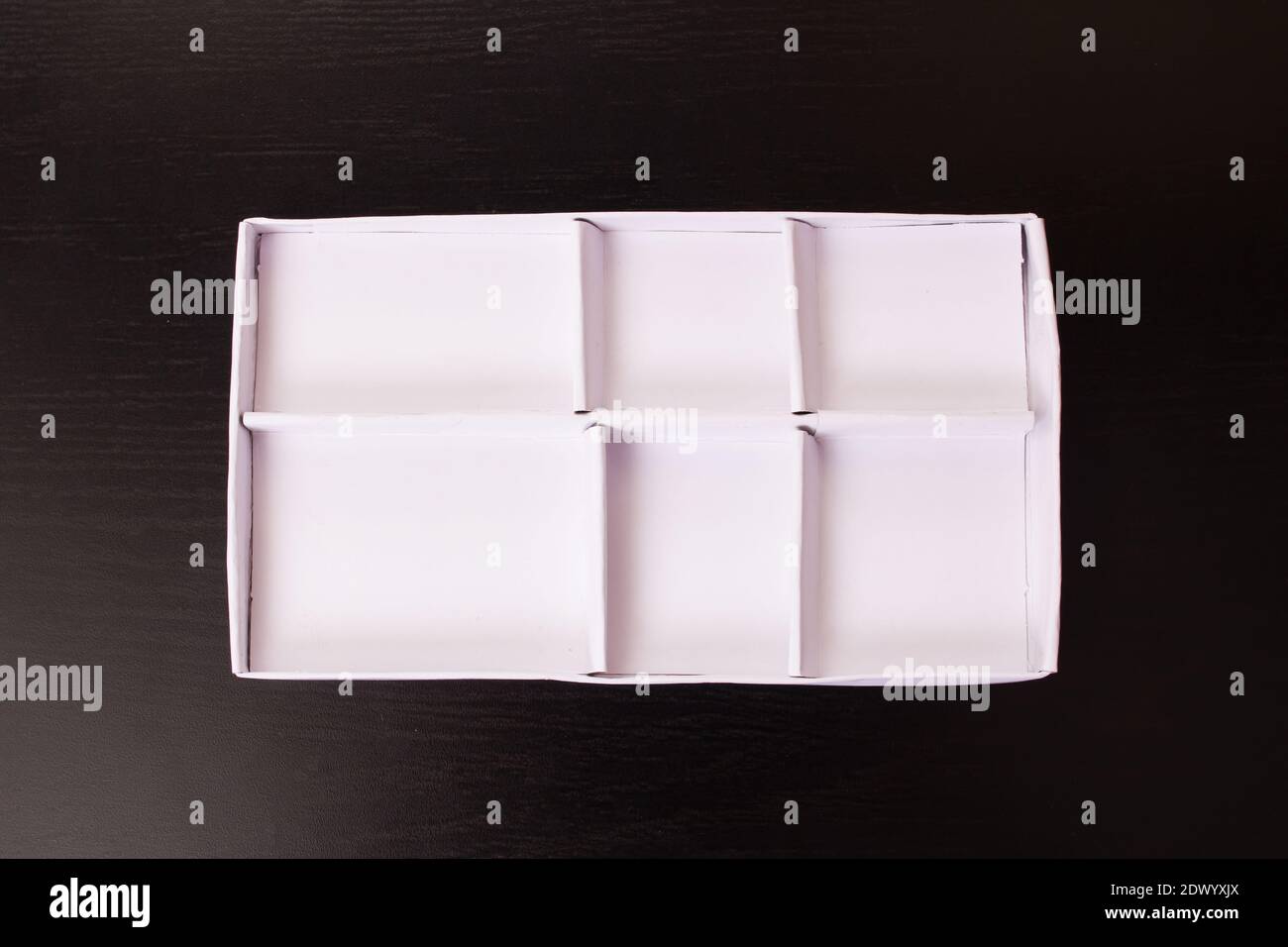 White box with cells on wooden table Stock Photo - Alamy