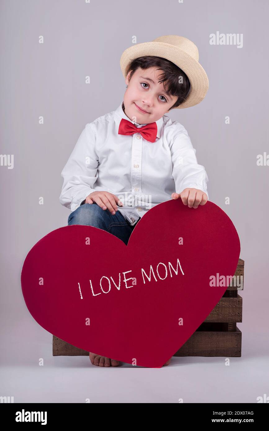Portrait Of Boy With Heart Shape With Text Sitting Against Gray ...