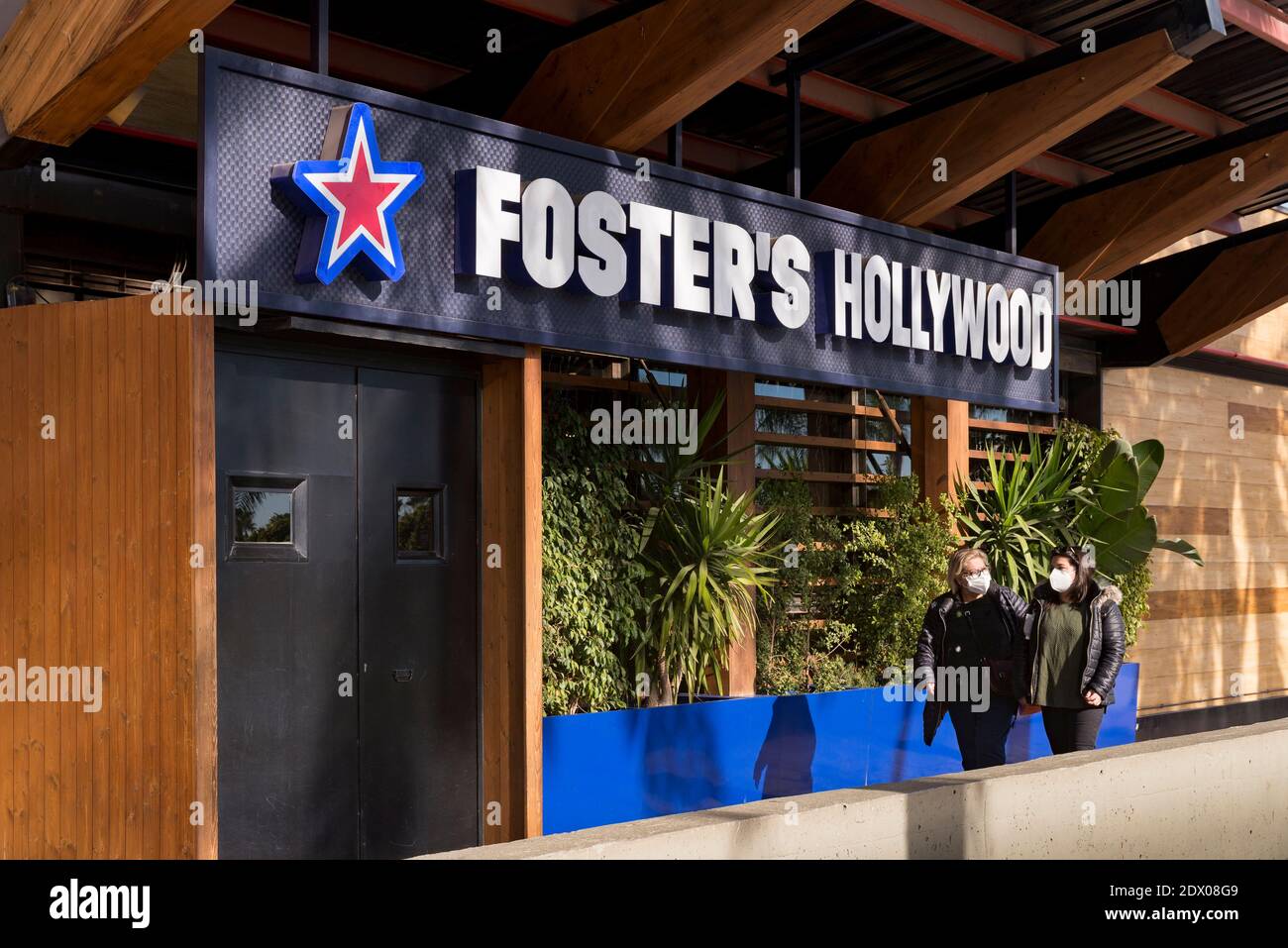 Two women wearing face masks walk in front of the fast food restaurant ...