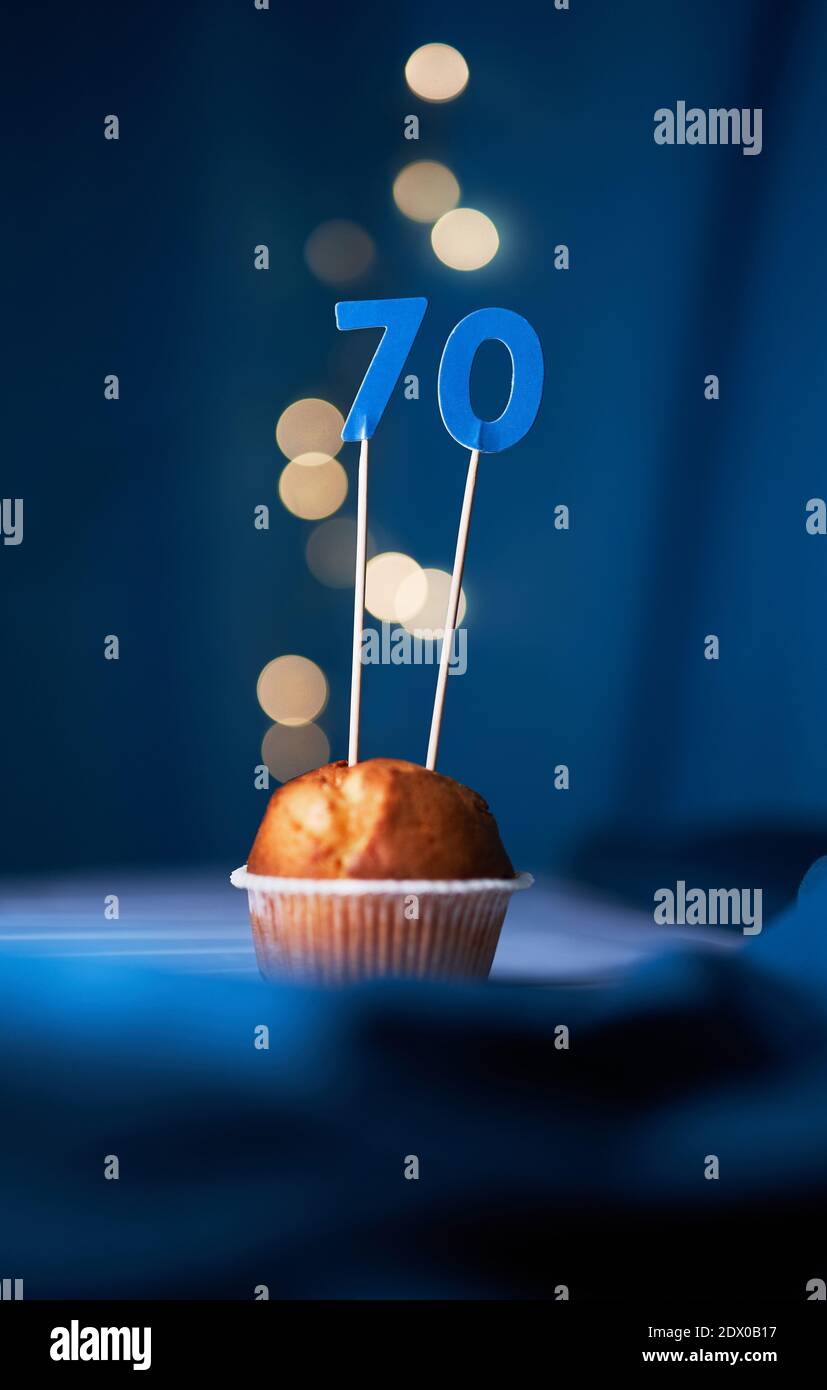 Birthday cake or muffin with seventy (70) number and lights on the blue ...
