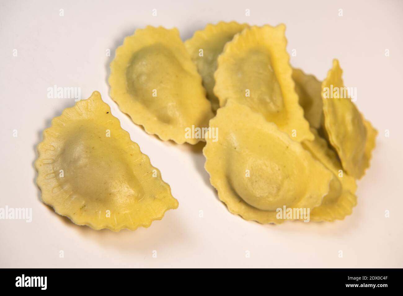 Tasty raw ravioli with flour and spinach on white background, process ...