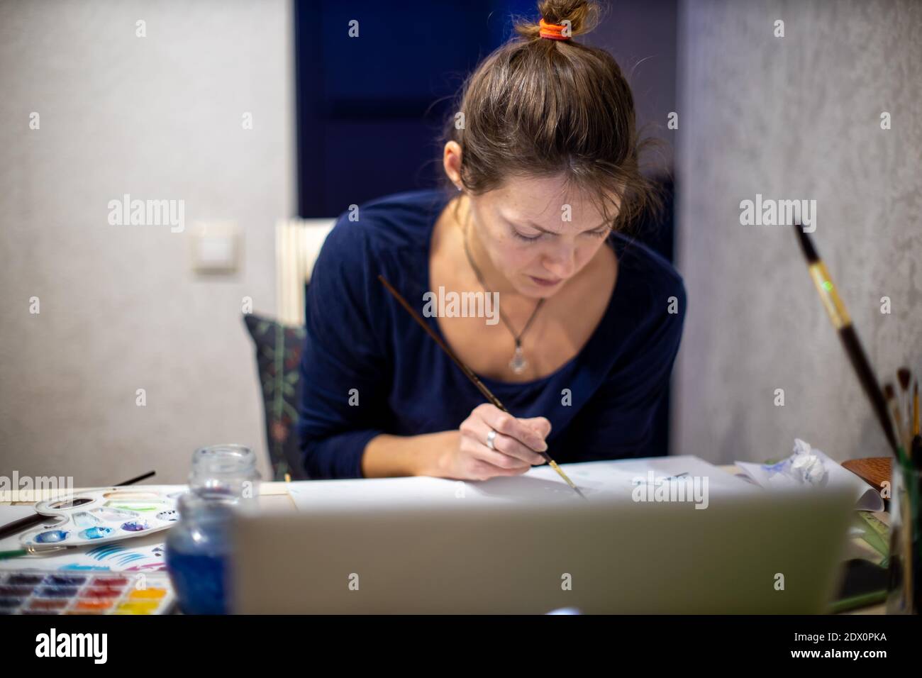 Portrait of creative young woman seated at table in an artists ...