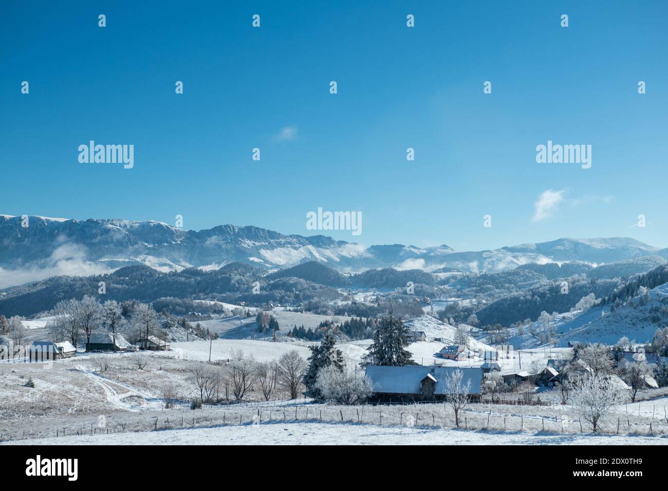 A beautiful shot of open fields covered with snow with a few houses on ...