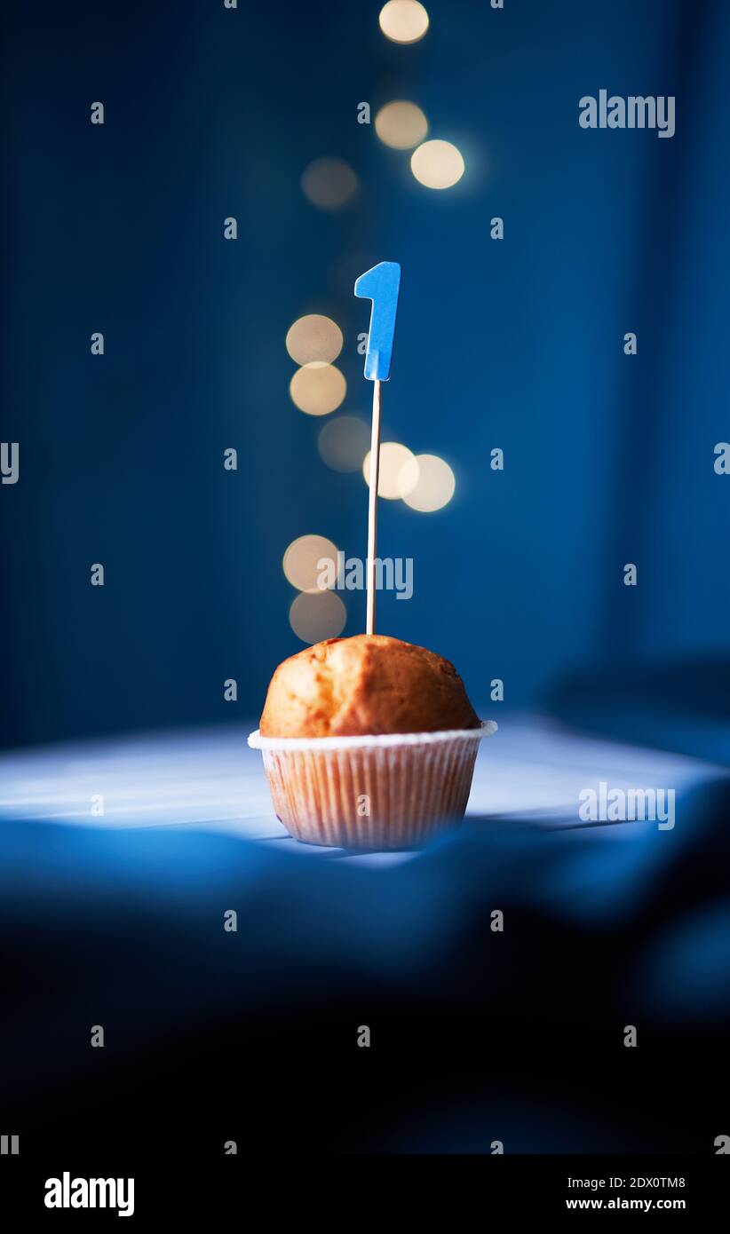 Birthday cake or muffin with number one (1) and blurred lights on the ...