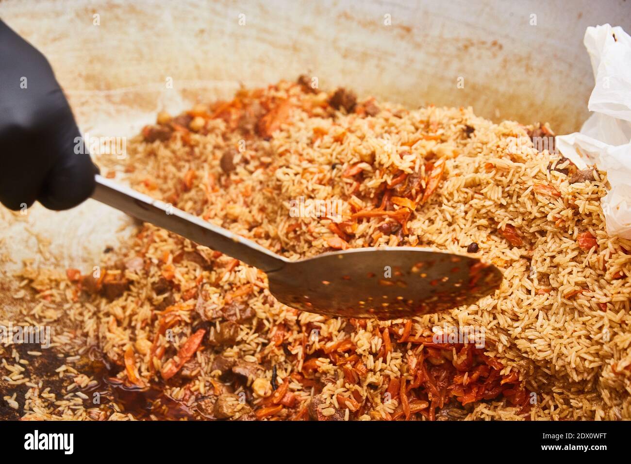 Asian traditional dish - pilaf. Cooking pilaf in a cauldron. Rice with ...