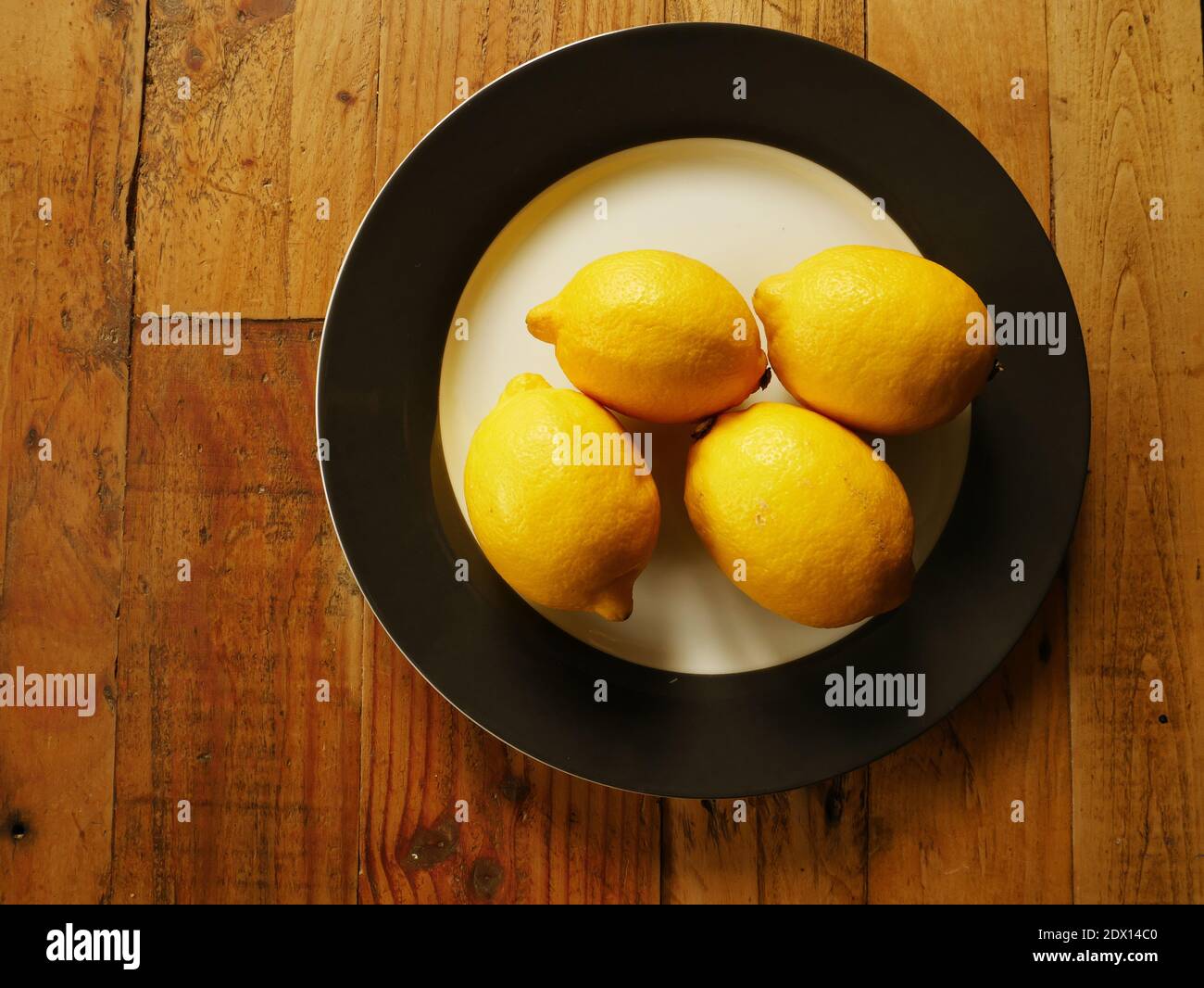 View from above on four lemons resting on a plate on a wooden ...