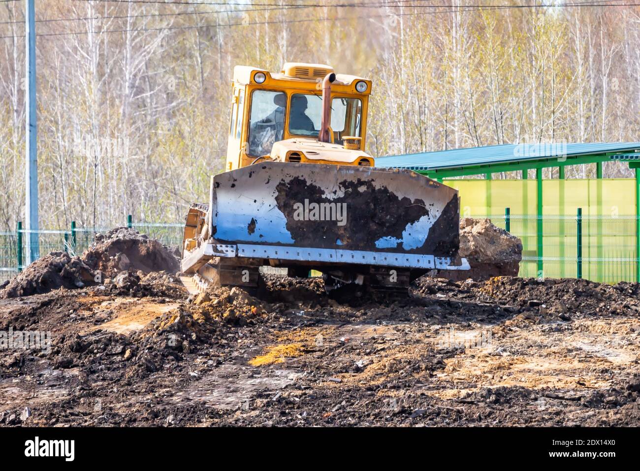 Yellow bulldozer leveling the ground at a construction site Stock Photo ...