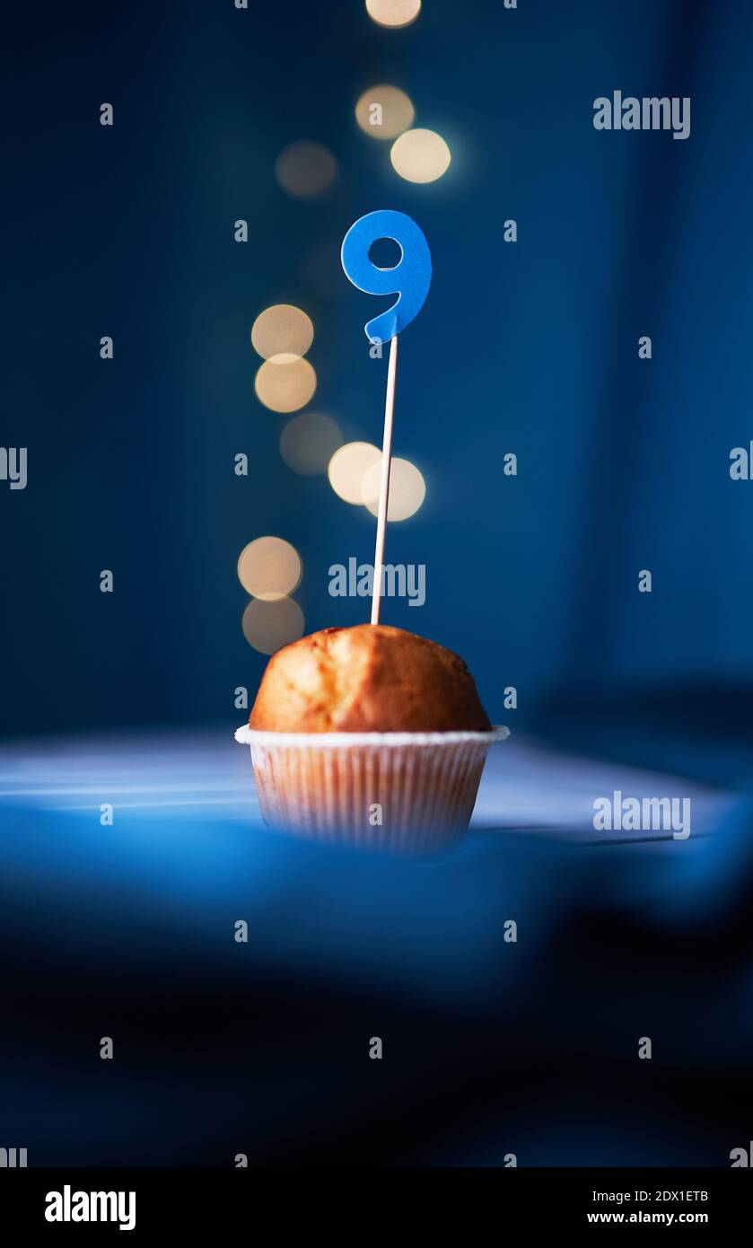 Birthday cake or muffin with nine (9) number and blurred lights on the ...