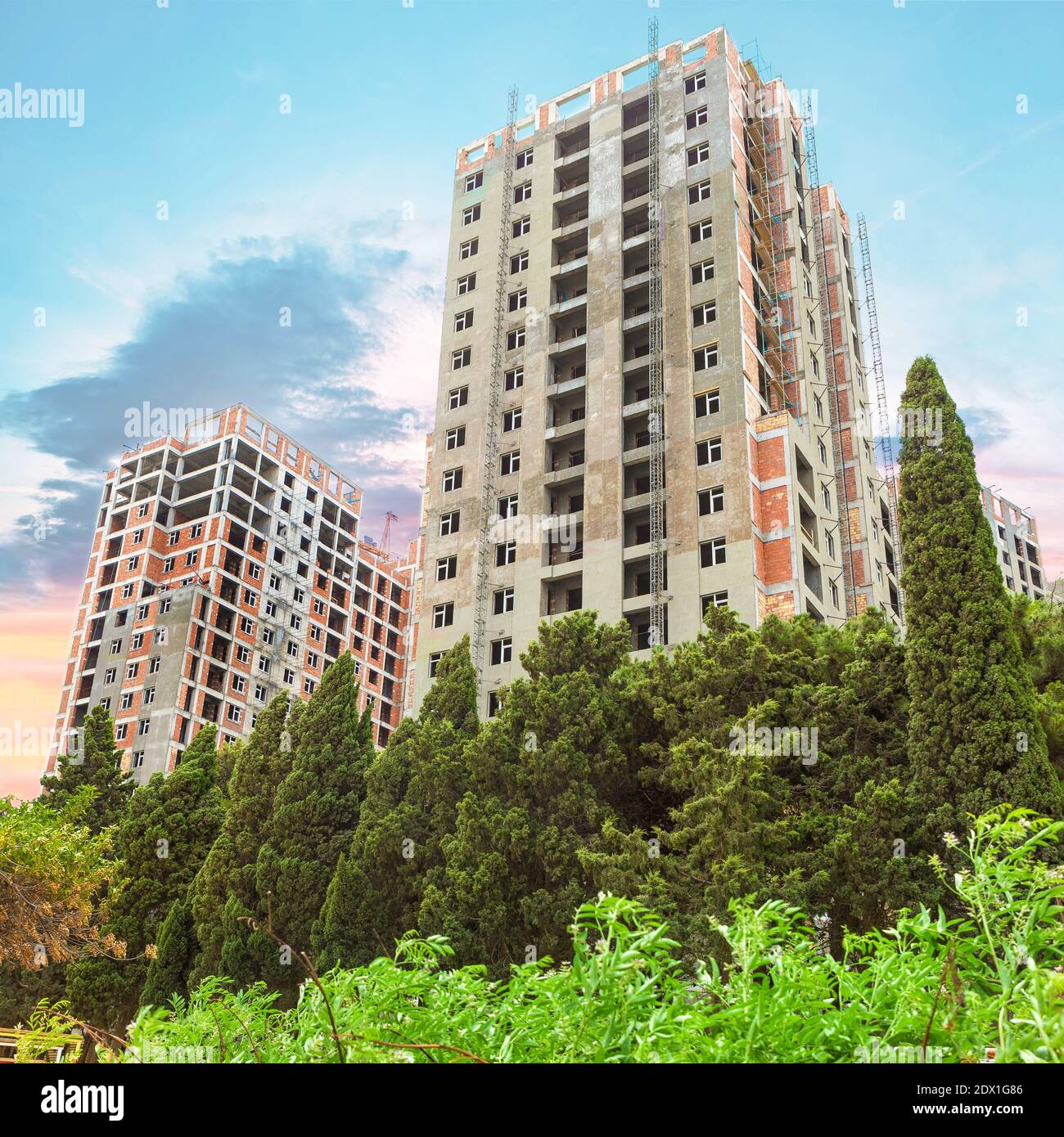 High buildings with scaffold and green trees at the construction site ...