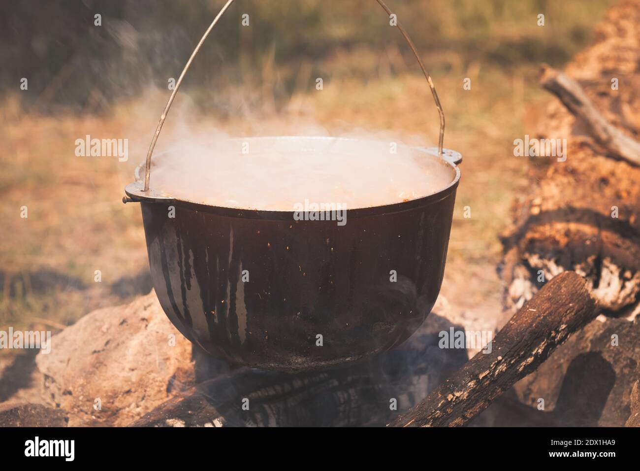 Boiling cauldron is on open fire, outdoor camping meal preparing Stock ...