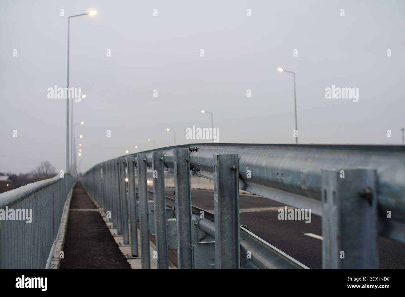 A view of a narrow sidewalk bridge lined with metal railings Stock ...
