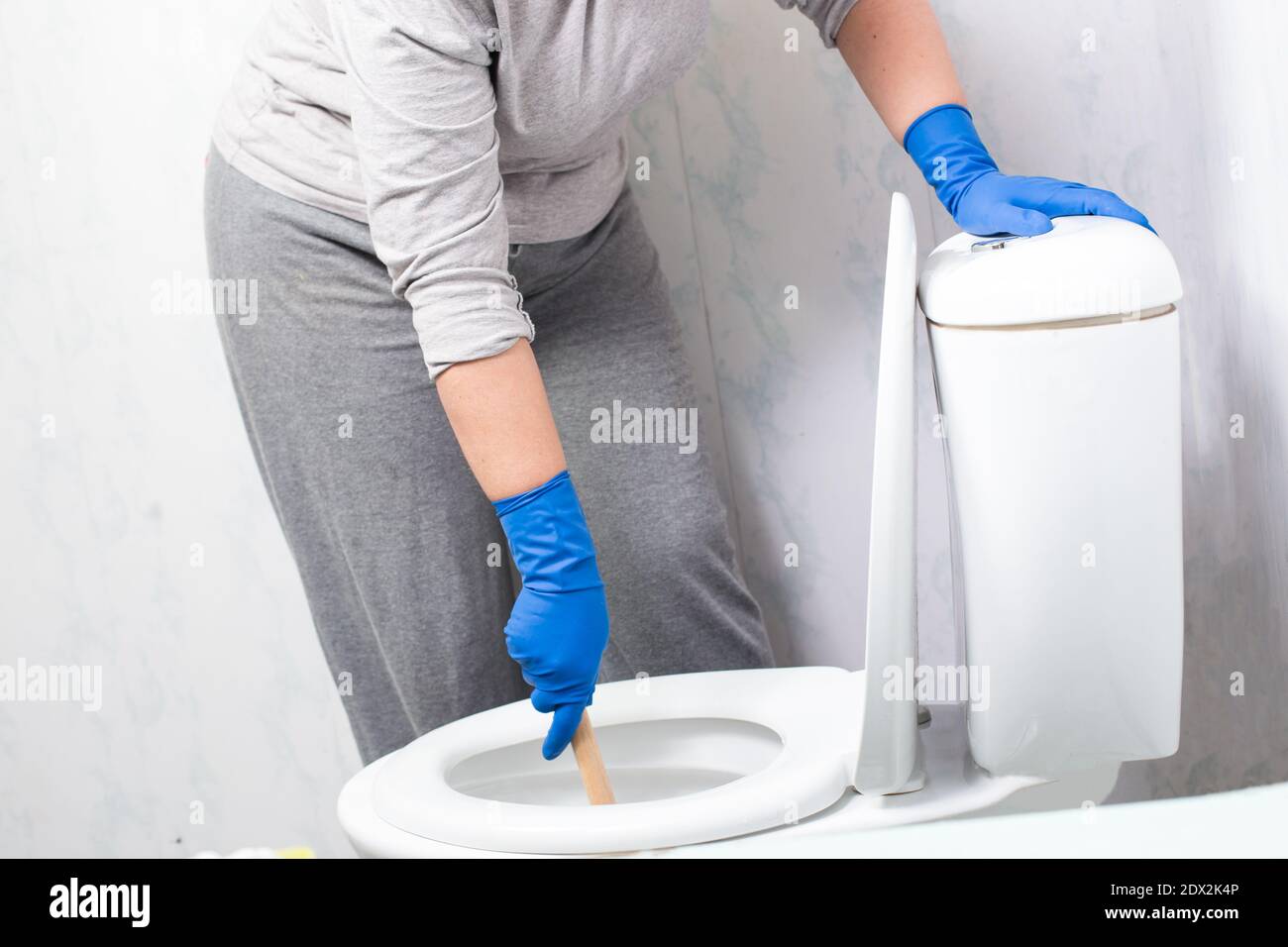 woman in gloves cleaning stuck toilet with suction cup Stock Photo - Alamy