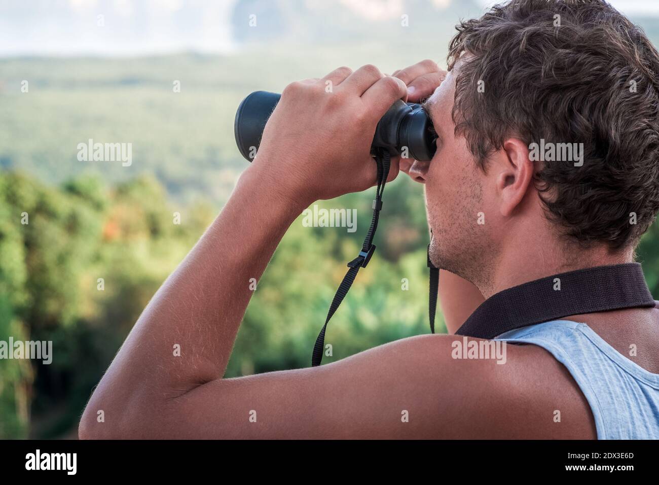 A young man looks into the distance through binoculars Stock Photo - Alamy