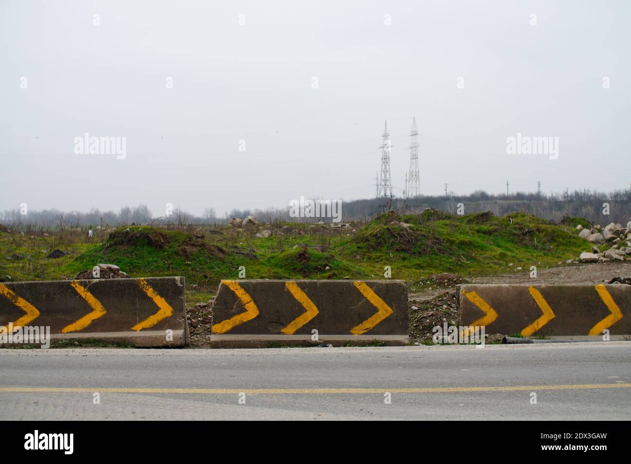 A highway lined with concrete barrier with yellow painted warning arrow ...