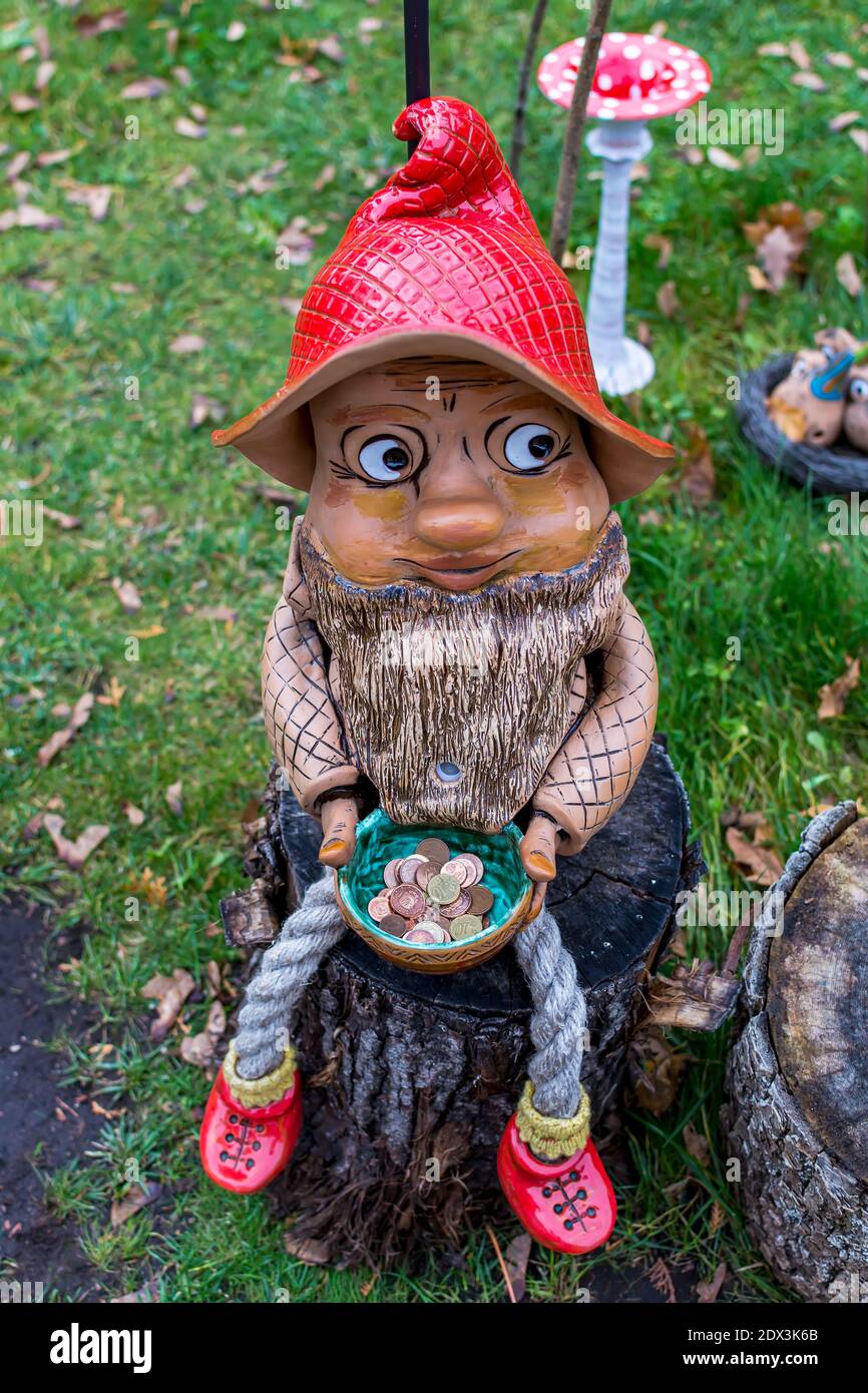 Ceramic dwarf wearing red hat sitting on the stub and gathering coins ...