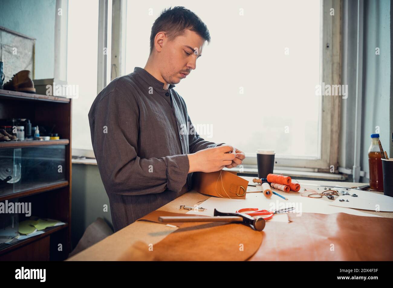 In a shoe workshop, a tanner makes handmade shoes using a hammer and ...