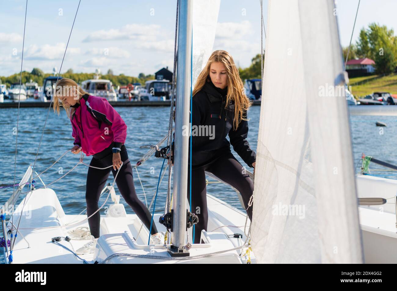 Before the competition on sailing boats two cute girls athletes equip ...