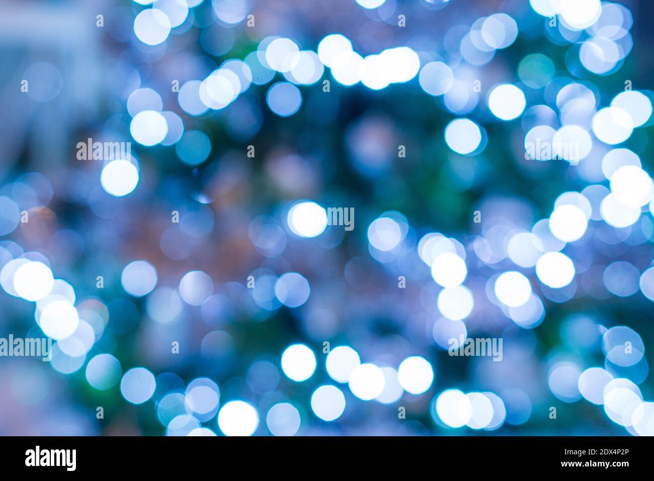 Abstract blue and white bokeh festoon on a dark green background. Bokeh ...