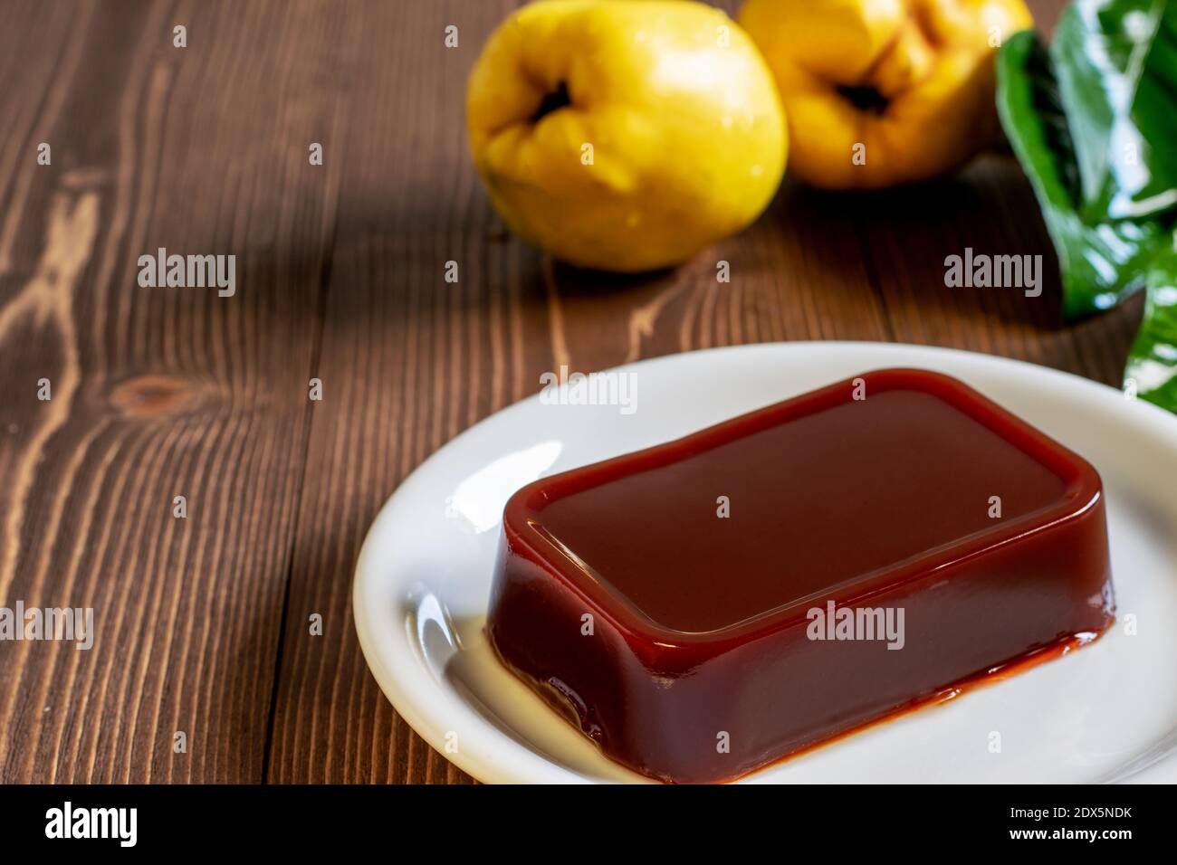 Homemade quince jam on the white plate, fresh ripe quince fruits on the ...