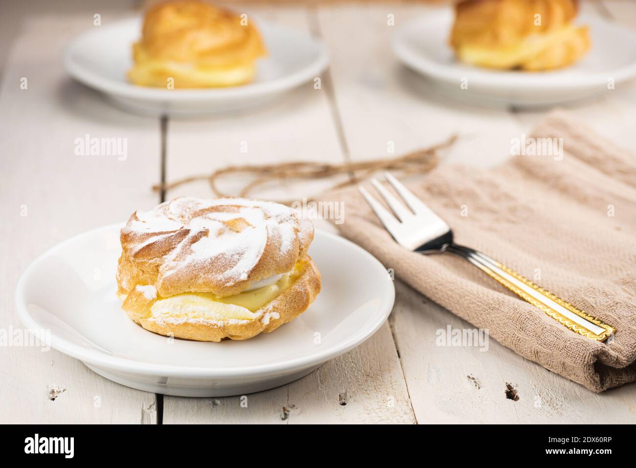 Profiterole cake on white wooden table. Creamy filling and crunchy ...