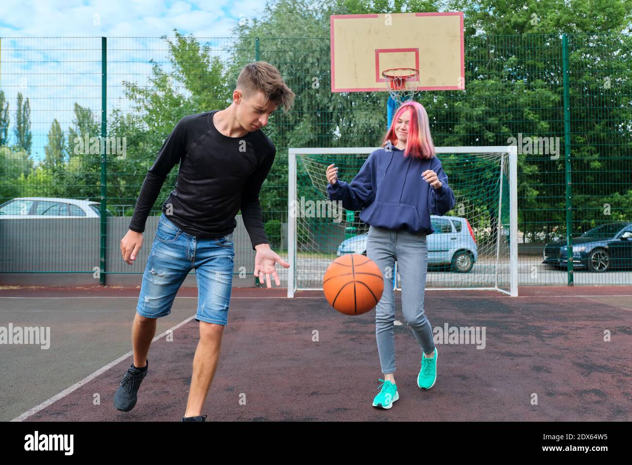 Teenagers guy and girl on an outdoor basketball court playing street ...