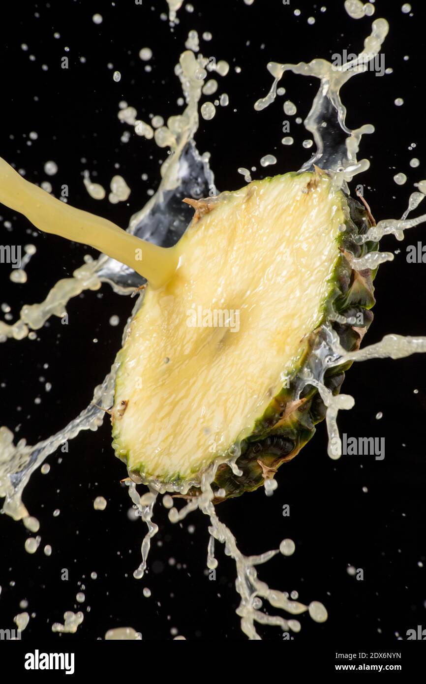 A slice of fresh pineapple splashed with pineapple juice. black ...