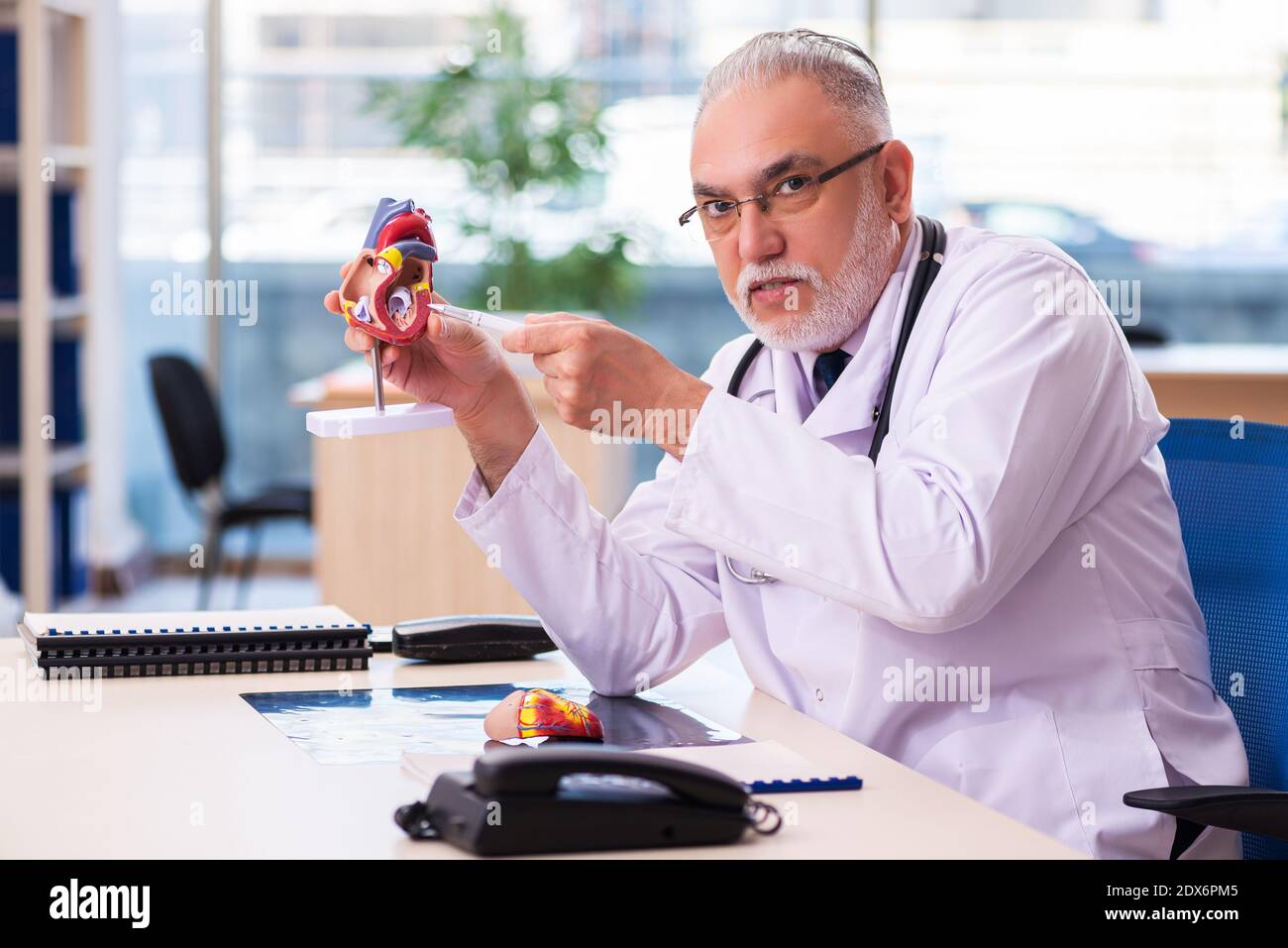 Old doctor cardiologist working in the clinic Stock Photo - Alamy