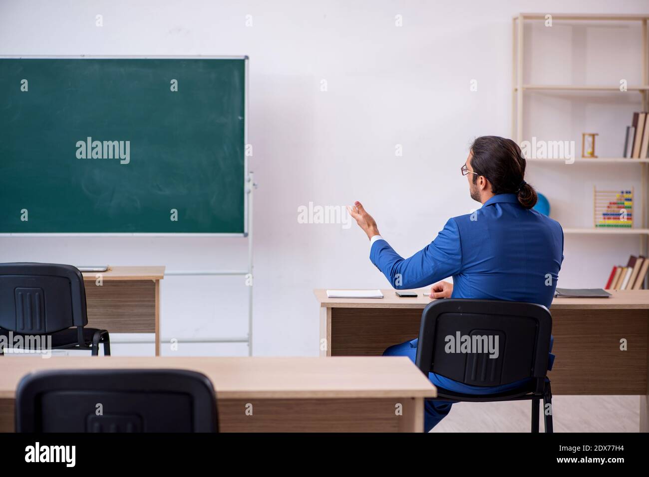 Young teacher in suit in front of green board Stock Photo - Alamy