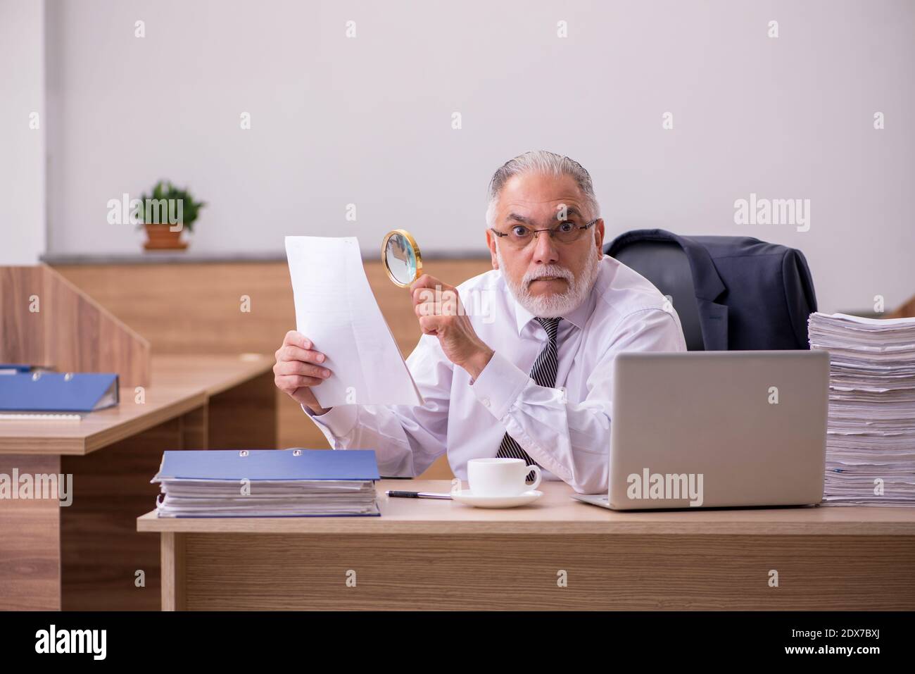 Old employee reading paper in the office Stock Photo - Alamy