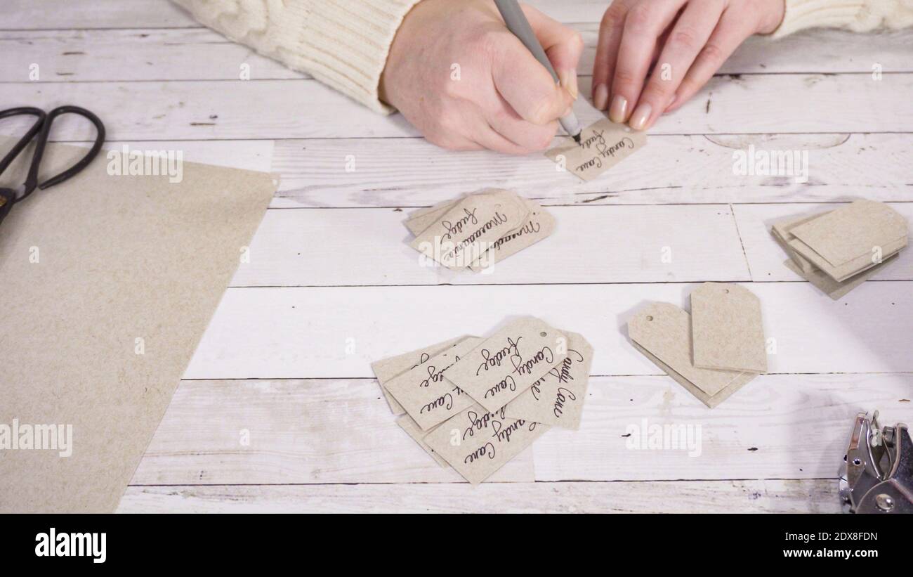Step by step. Labeling brown paper gift tags with a black marker Stock ...