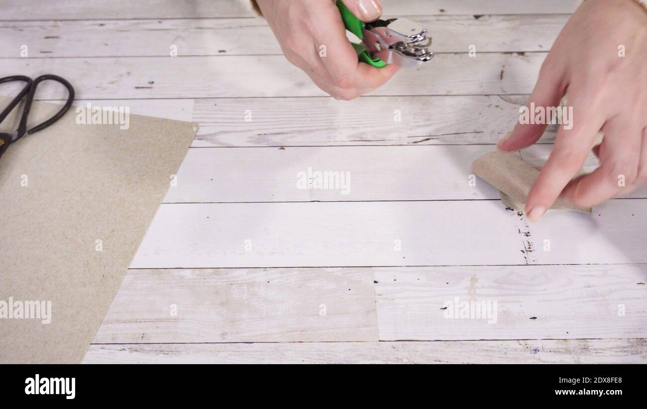 Step by step. Cutting out gift tags from brown paper with a paper punch ...