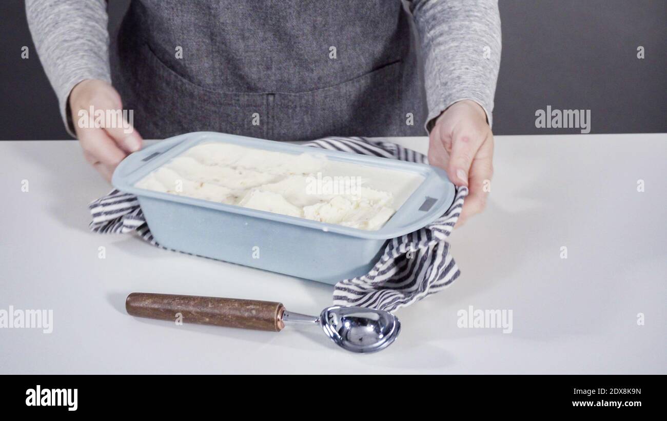 Scooping homemade coconut ice cream into a glass ice cream bowl Stock ...