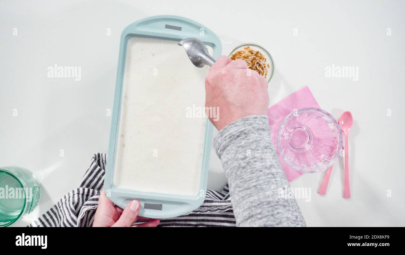 Flat lay. Scooping homemade coconut ice cream into a glass ice cream ...