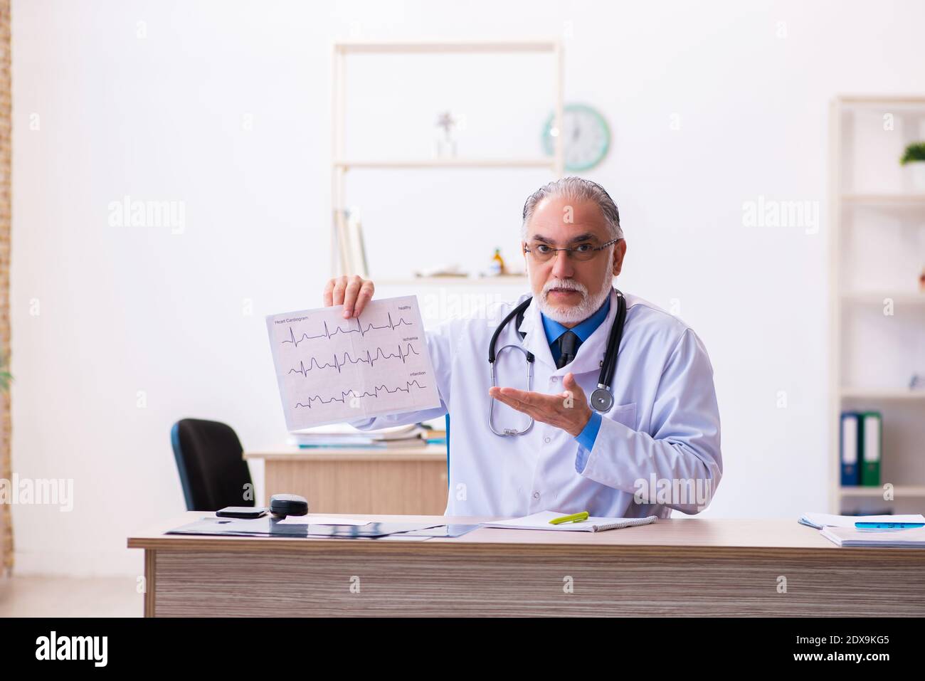Senior male doctor cardiologist looking electrocardiogram Stock Photo ...
