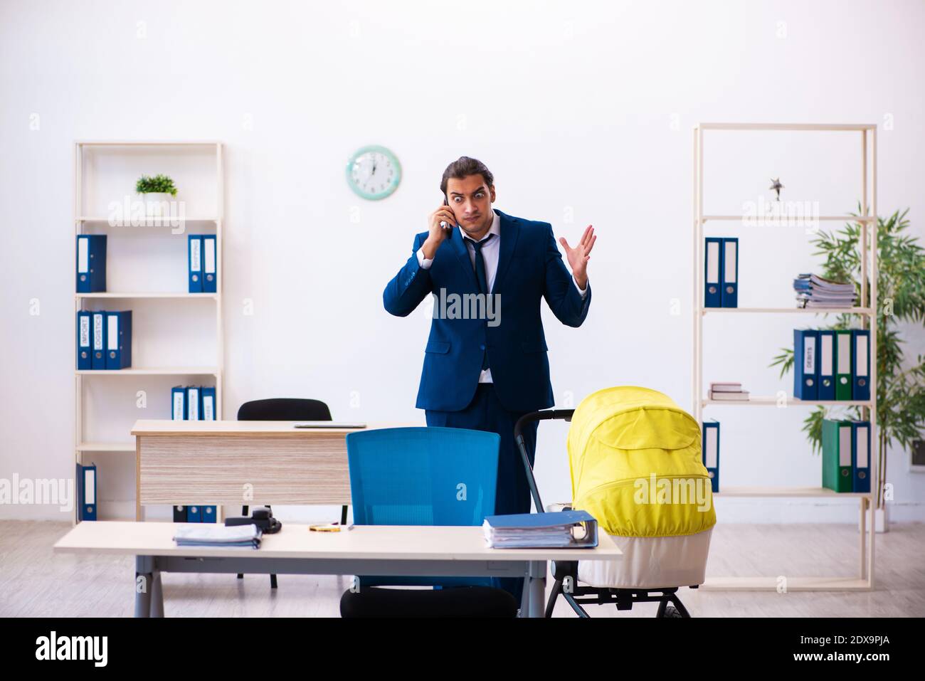Young employee looking after kid at workplace Stock Photo - Alamy