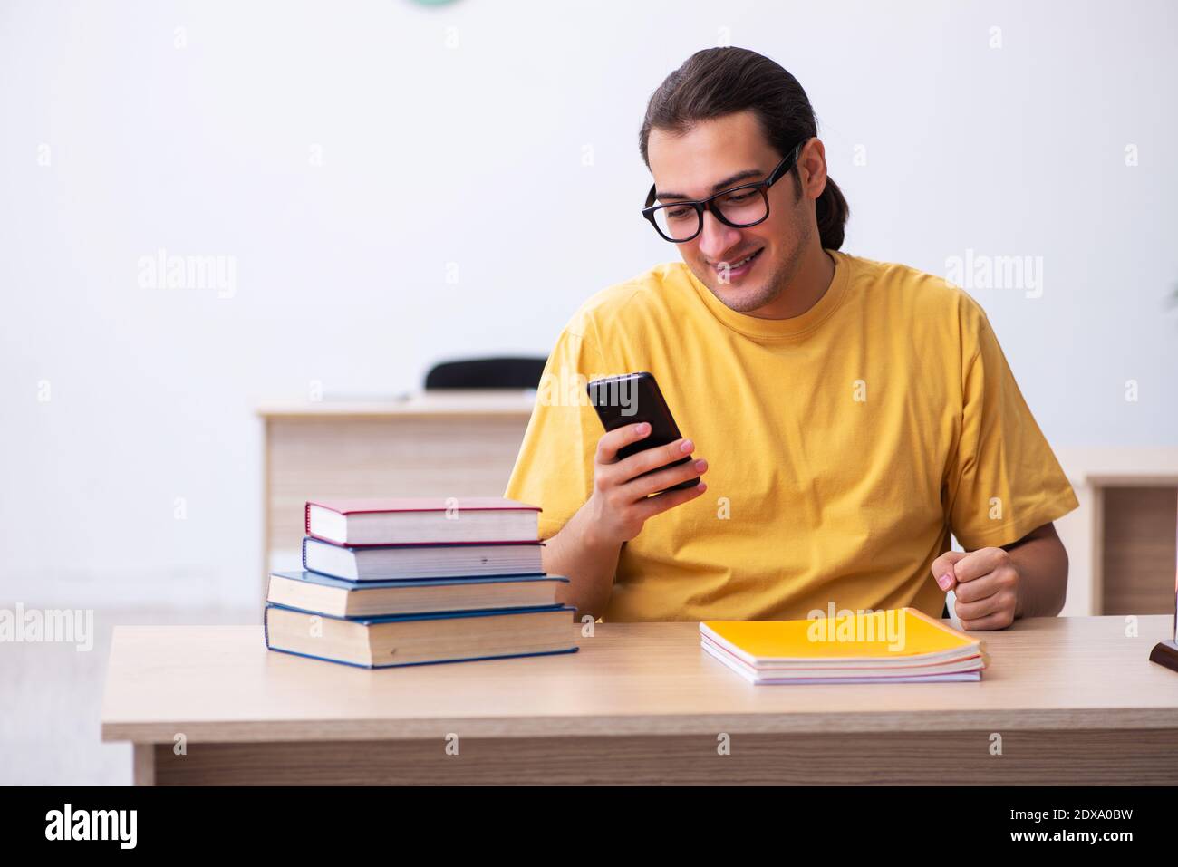 Young student holding mobile phone during exam preparation Stock Photo ...
