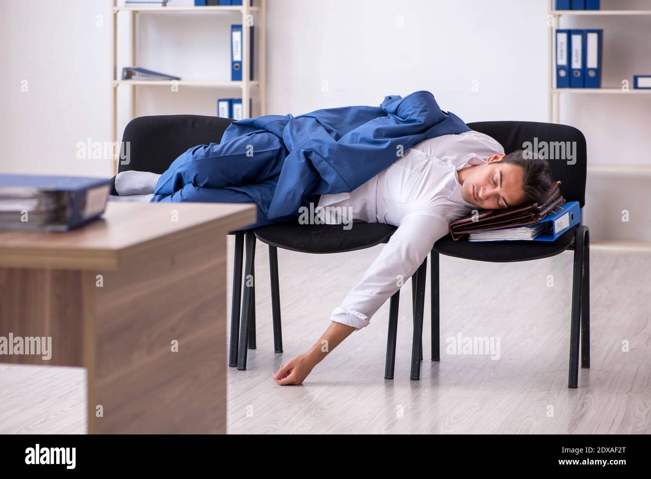 Young employee sleeping in the office on chairs Stock Photo - Alamy