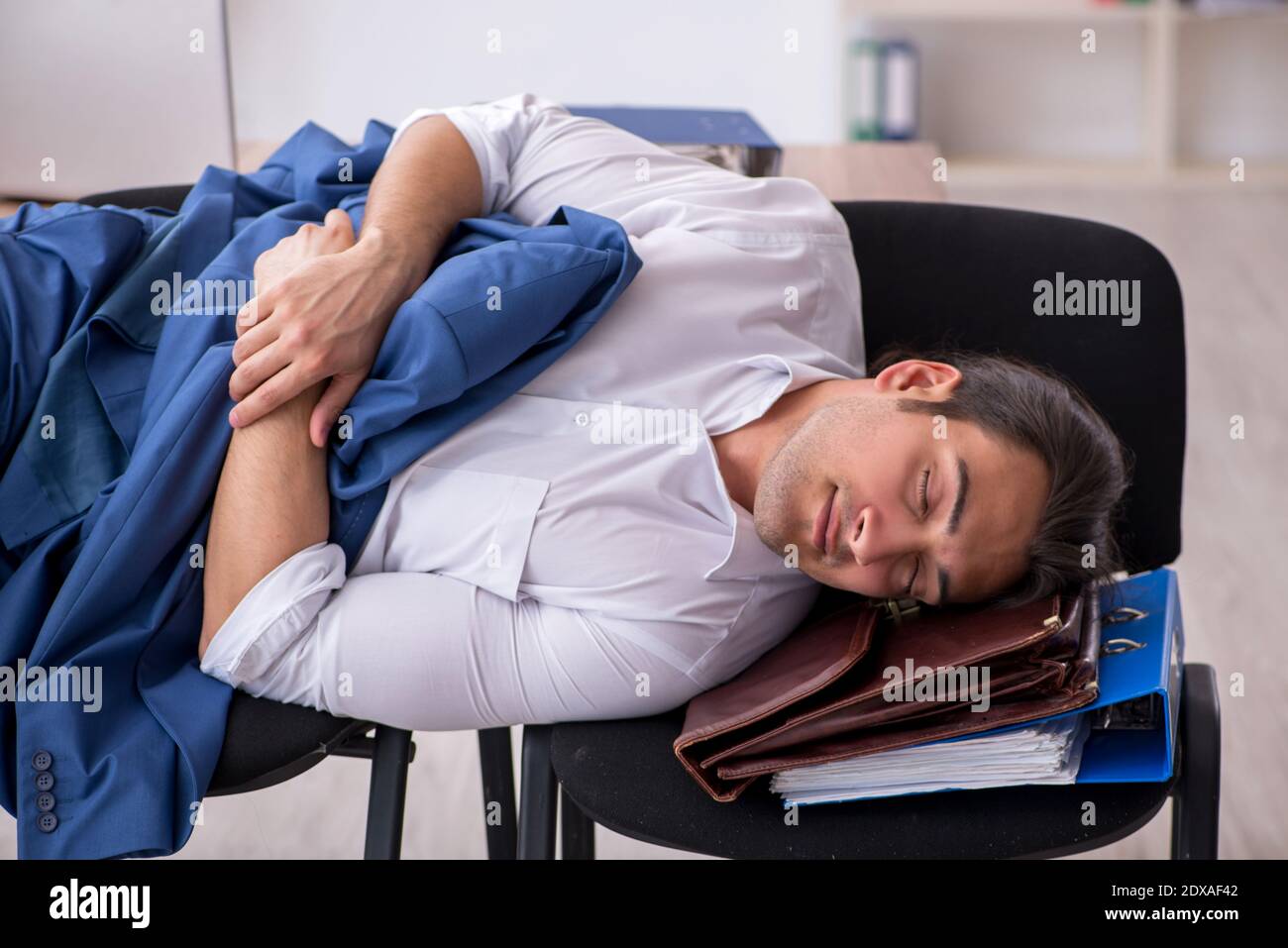 Young employee sleeping in the office on chairs Stock Photo - Alamy