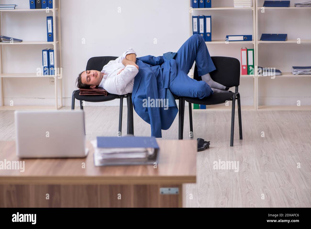 Young employee sleeping in the office on chairs Stock Photo - Alamy