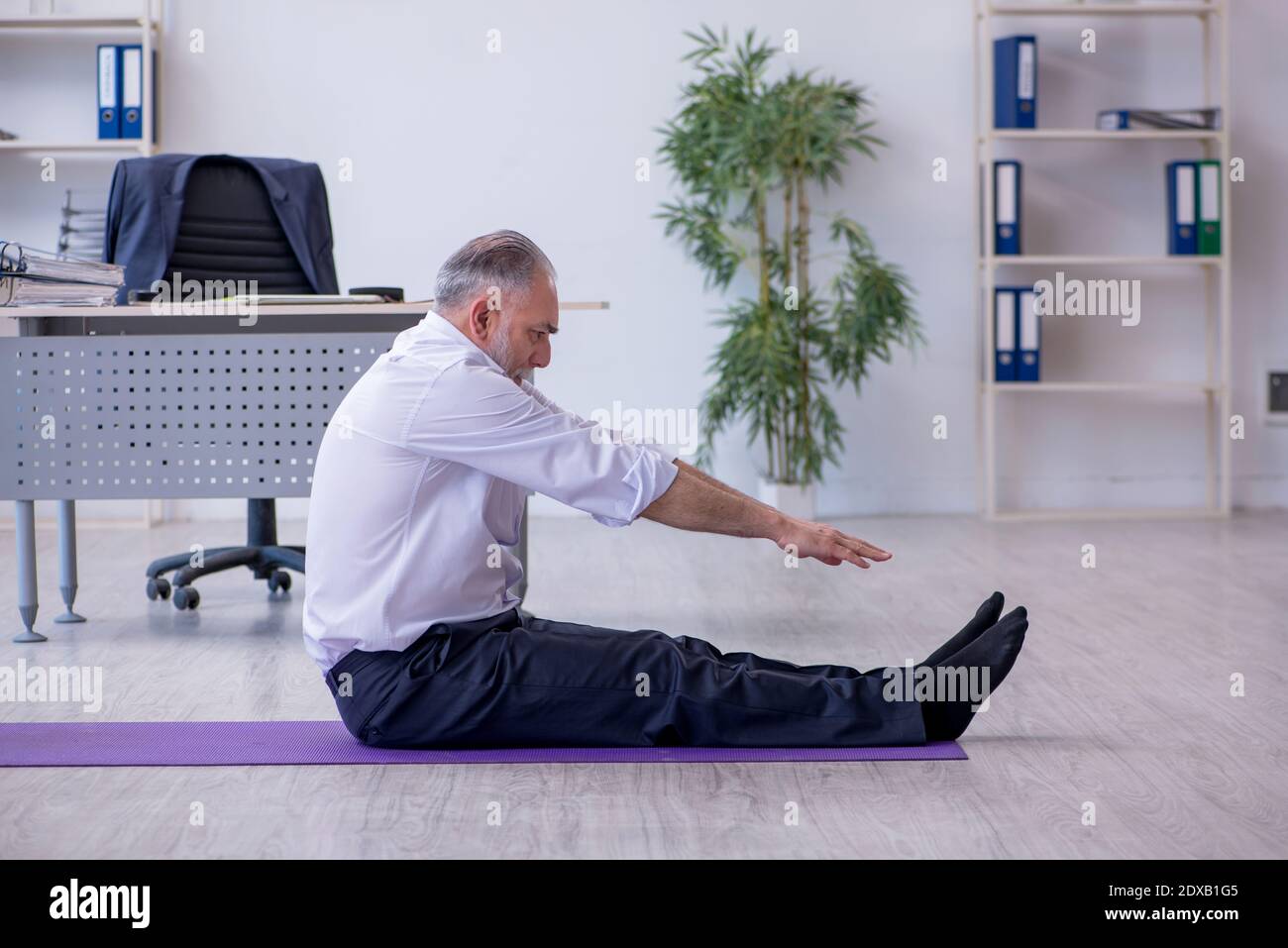 Aged employee doing physical exercises during break Stock Photo - Alamy