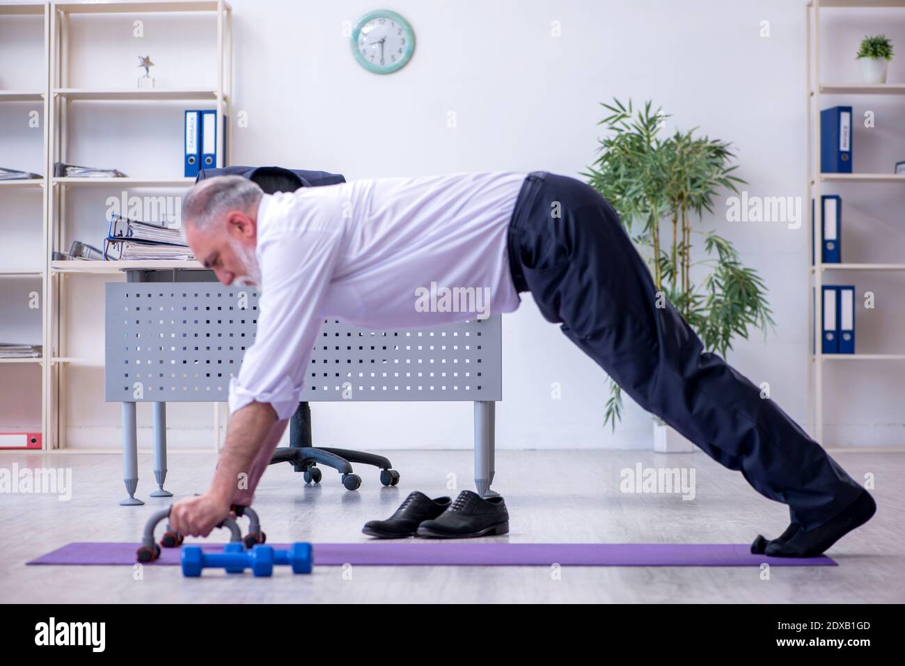 Aged employee doing physical exercises during break Stock Photo - Alamy