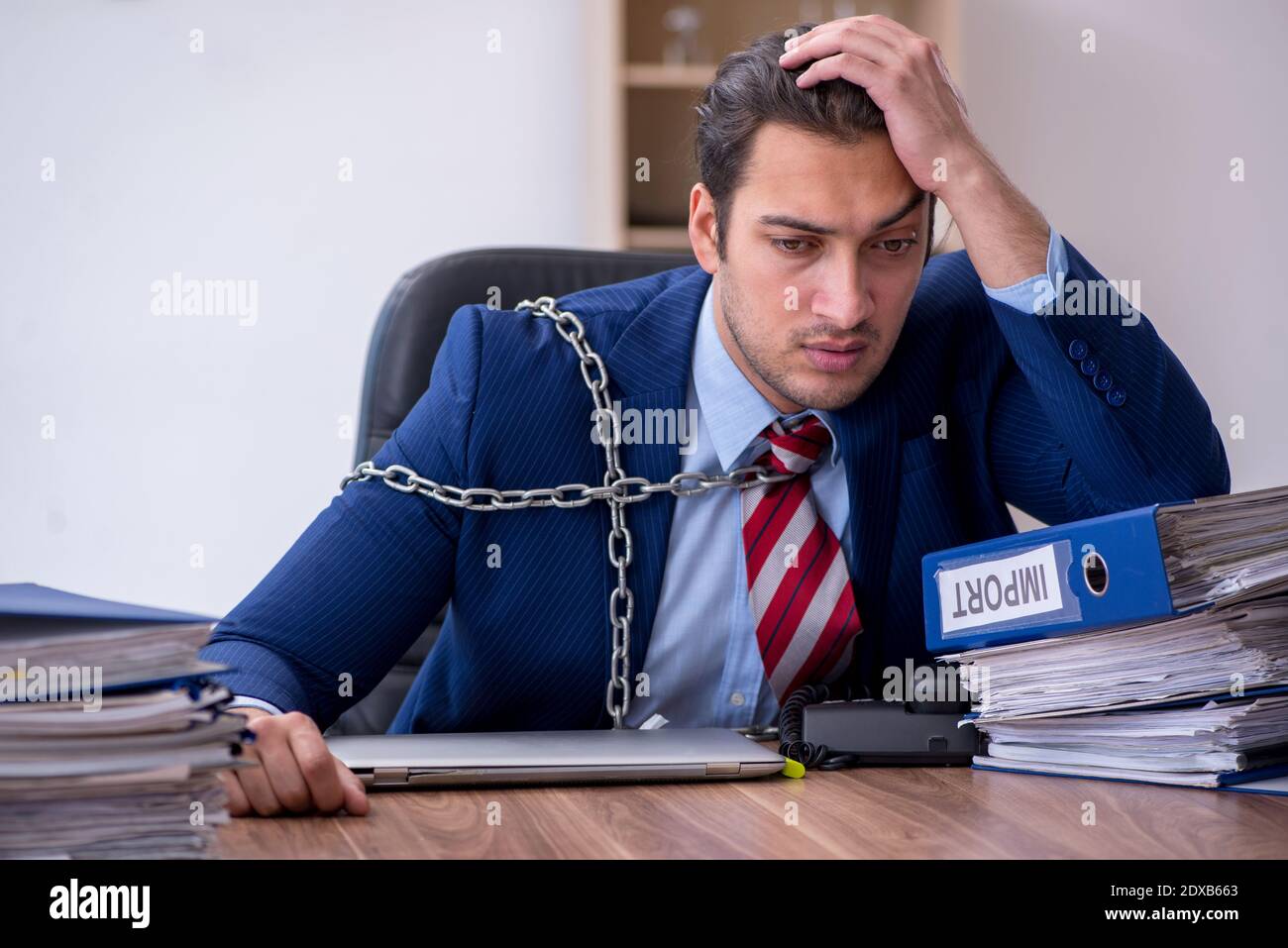 Chained employee unhappy with excessive work in the office Stock Photo ...