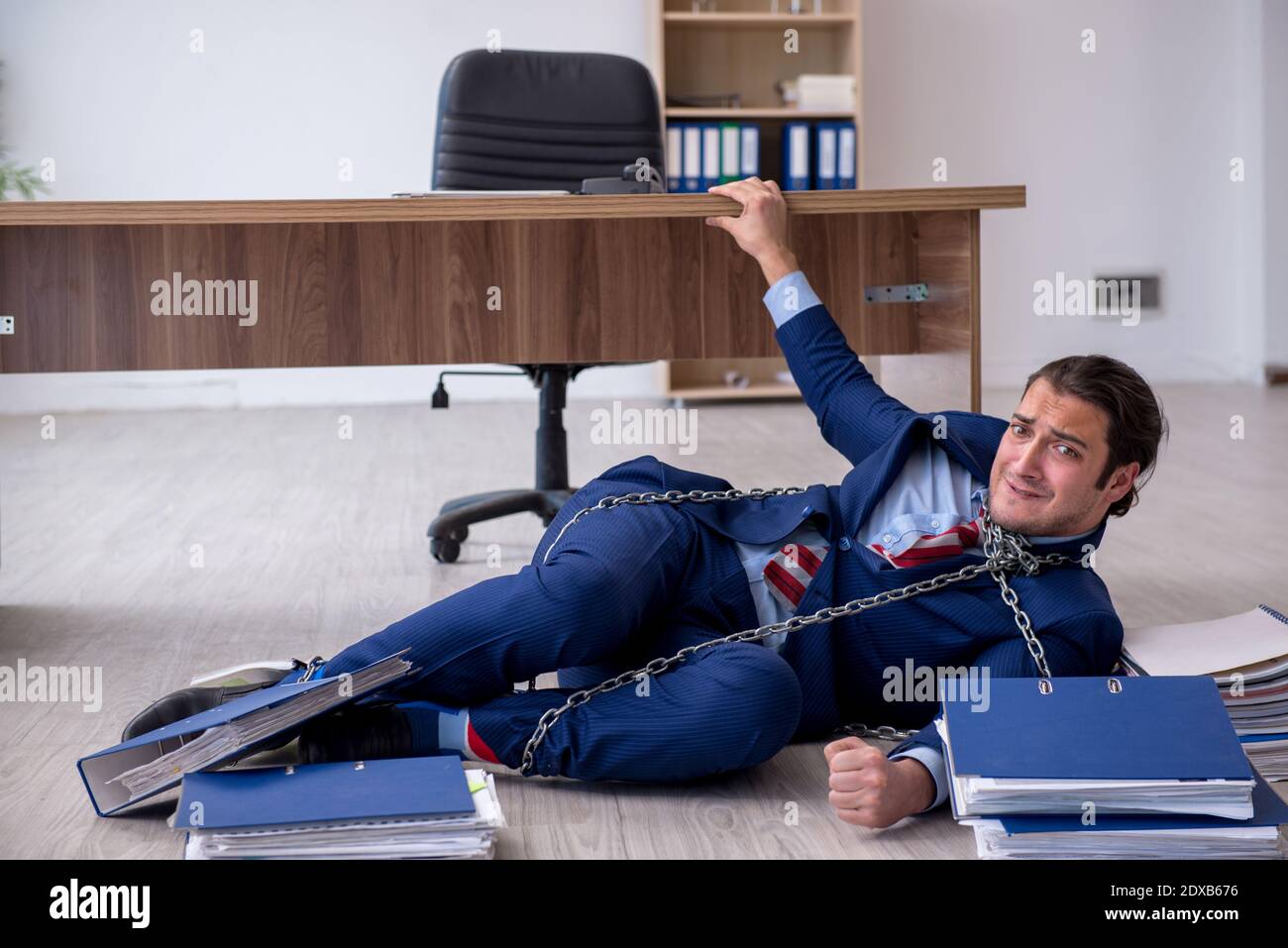 Chained employee unhappy with excessive work in the office Stock Photo ...