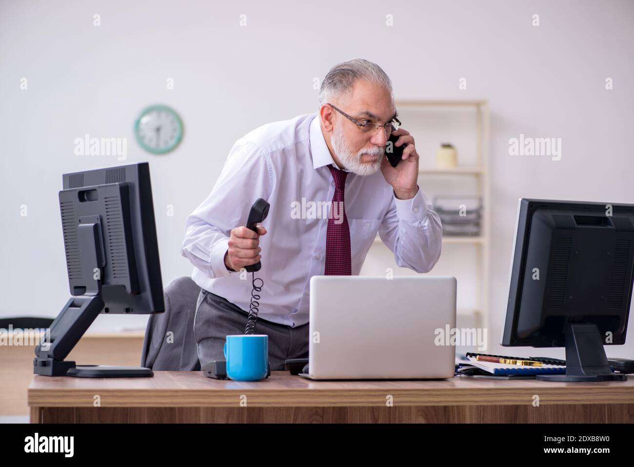Old boss sitting at desktop in the office Stock Photo - Alamy