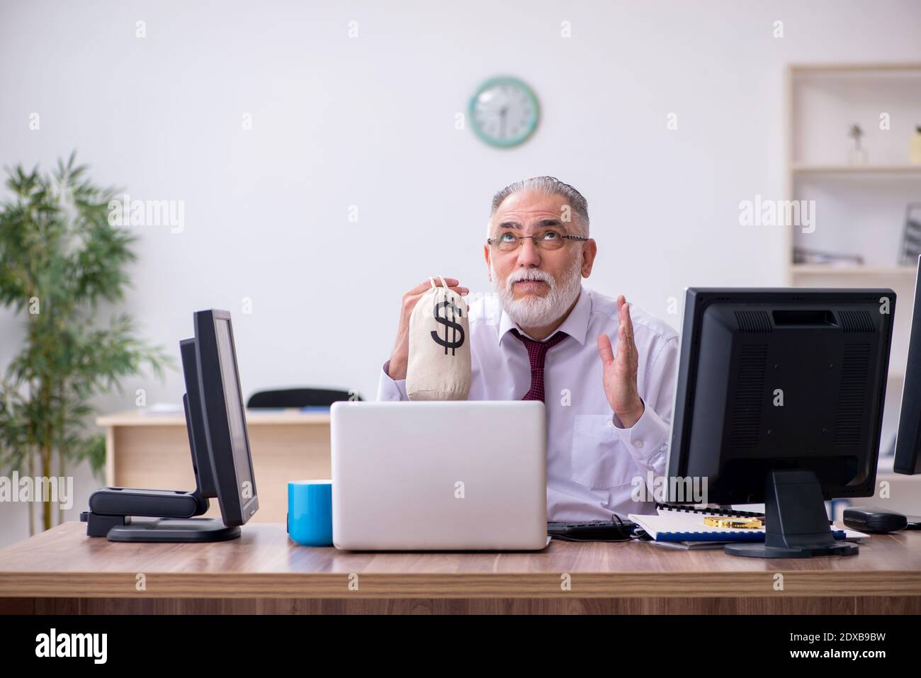 Old boss sitting at desktop in the office Stock Photo - Alamy