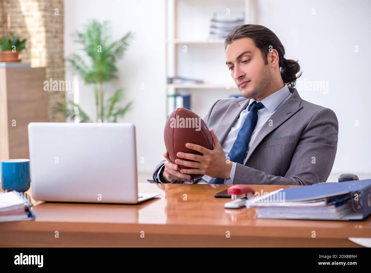 Male employee with rugby ball in the office Stock Photo - Alamy
