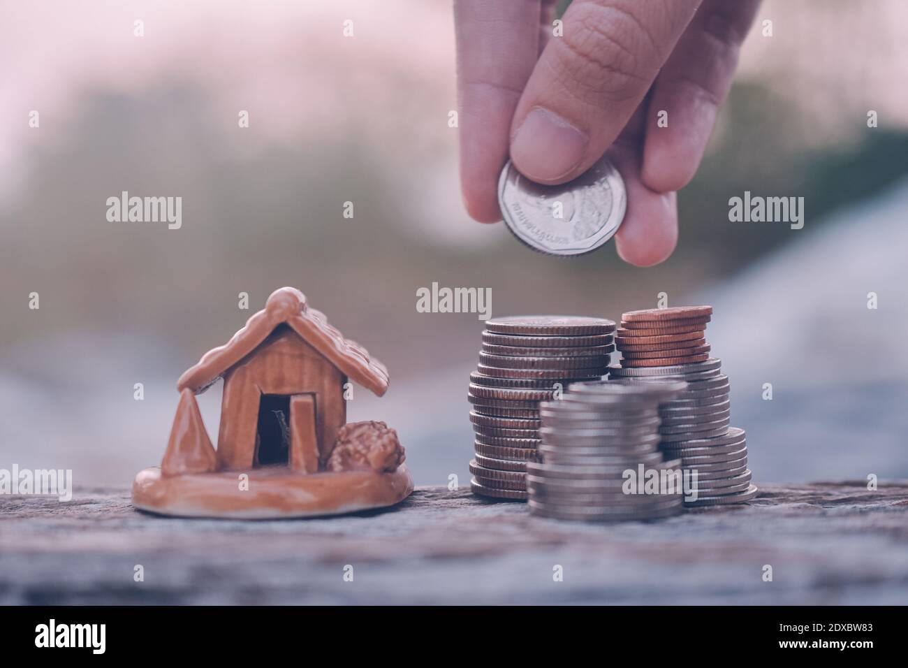 Hand select coins stack home model on wood table Stock Photo - Alamy
