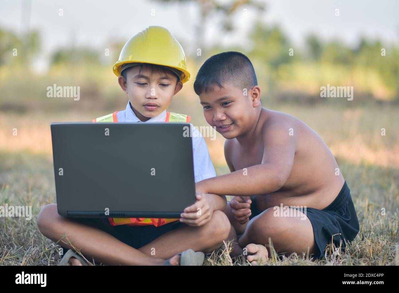 Boy kid and friend use computer laptop sitting outdoor learning by ...