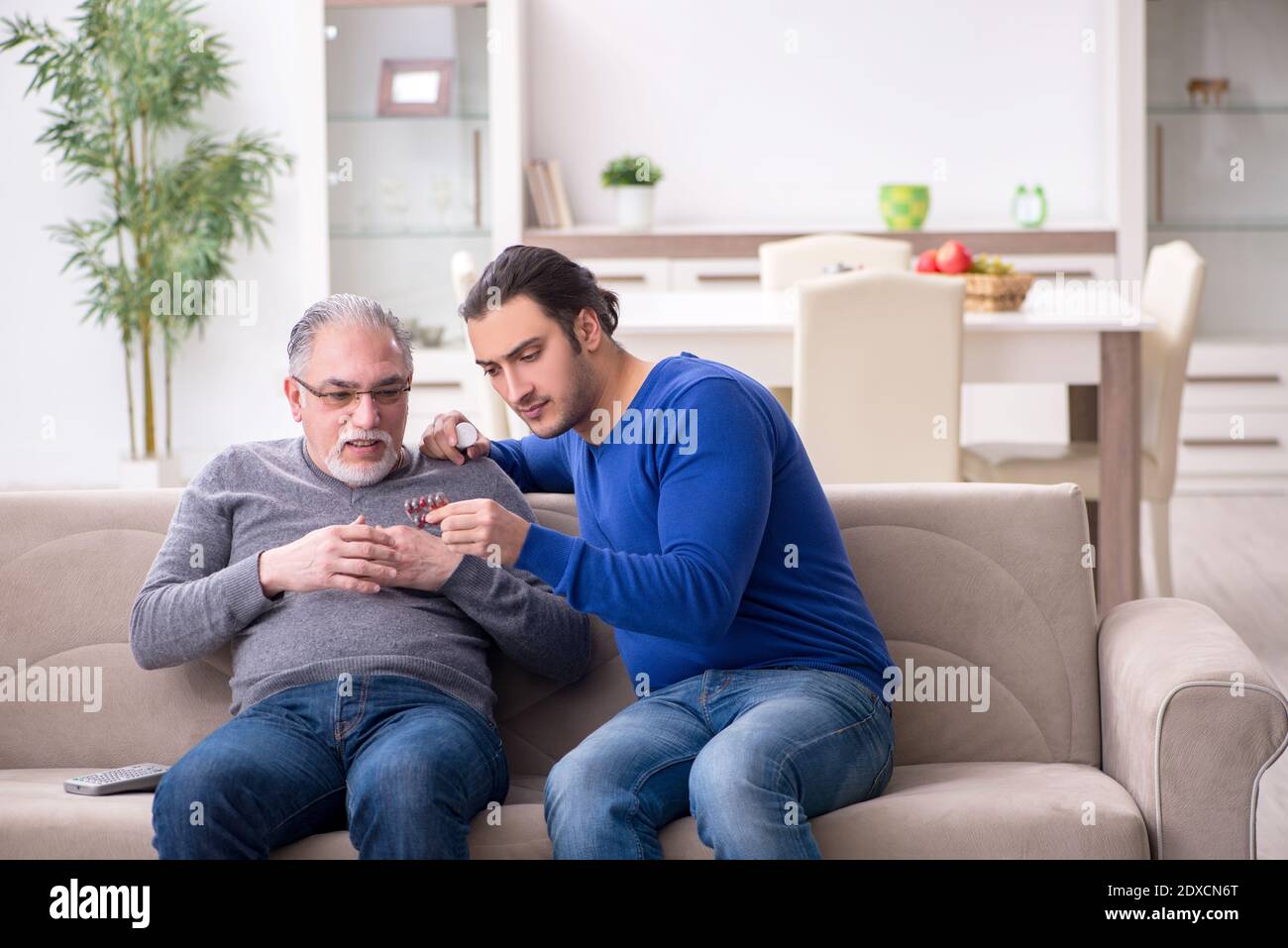 Young man looking after his sick father at home Stock Photo - Alamy